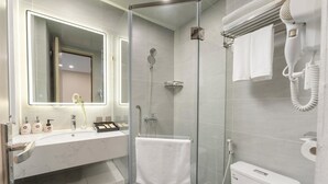 Uma casa de banho moderna com cabine de duche em vidro, lavatório branco com espelho e sanita.