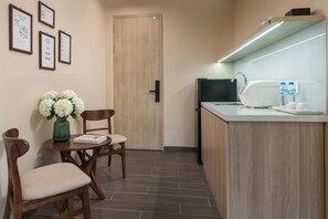 Uma cozinha compacta com área de refeições, porta de madeira e uma pequena mesa com um vaso de flores.