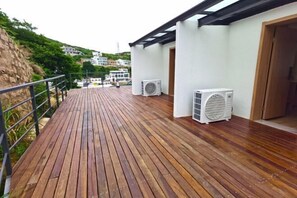 Um deck de madeira com duas unidades de ar condicionado, corrimão e um edifício com porta.