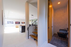 Amplo interior com escada que dá para um segundo andar, área de cozinha e espaço de jantar com vista.
