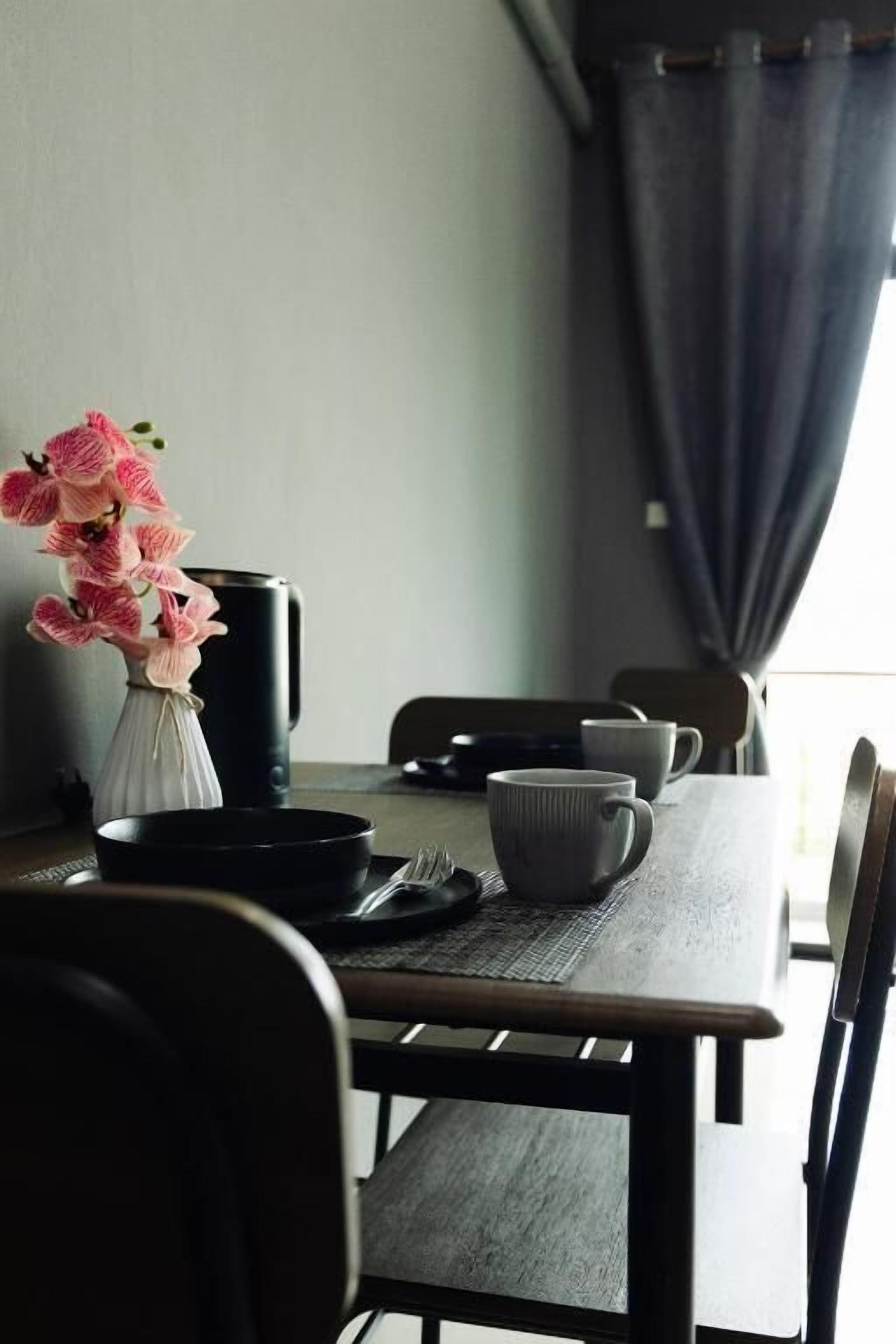 Uma mesa de jantar com um vaso de flores, uma tigela e uma caneca.