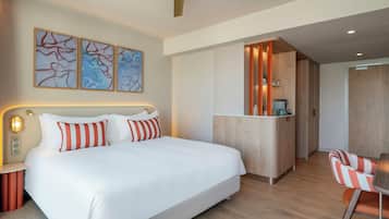 Quarto de hotel com uma cama grande, uma escrivaninha e uma cadeira. Há três obras de arte fixadas na parede acima da cama.