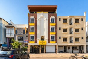 Um edifício de vários andares com uma placa indicando 'The Hosteller' e um centro de cirurgia de plástico e materiais compósitos.