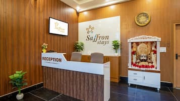 Balcão de recepção com uma placa indicando 'Saffron Stays' e um relógio na parede.
