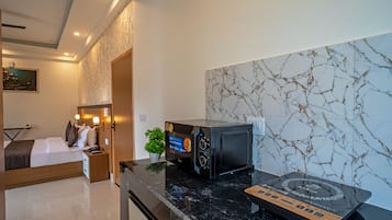 Quarto de hotel moderno com cama, uma pequena escrivaninha, micro-ondas e parede com padrão marmorizado.