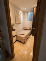 Quarto com cama, mesa de cabeceira, janela e porta.
