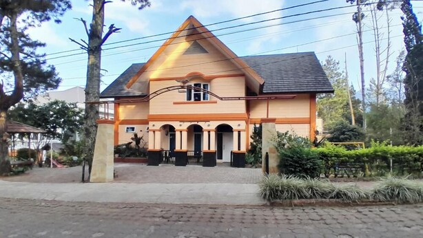 Um edifício de dois andares com telhado empena e entrada central.