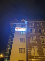 Edifício de hotel com uma placa indicando 'BATIN OTEL' e um número de contato.