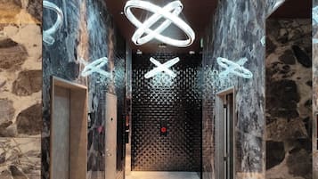 Corredor com paredes de mármore e luminária de design geométrico.
