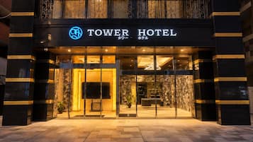 Exterior do Tower Hotel com fachada moderna, ampla entrada de vidro e placa de hotel bem visível.
