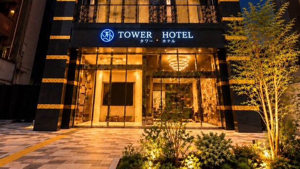 Um hotel com vários andares e entrada destacada, com placa indicando ser o 'TOWER HOTEL'.