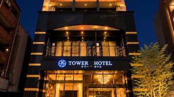 Um hotel com vários andares e entrada destacada, com placa indicando ser o 'TOWER HOTEL'.