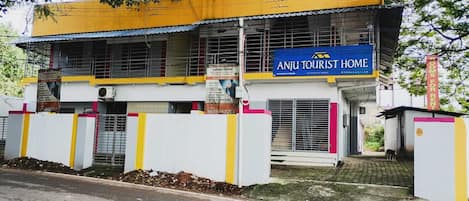 Um edifício de dois andares com uma placa indicando 'Anju Tourist Home' e uma placa que sinaliza quartos para alugar.