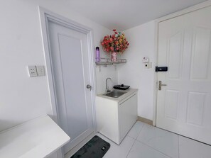 Cozinha compacta com pia, bancada pequena e porta com puxador.