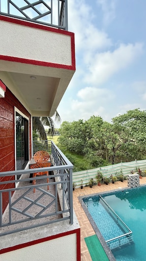 Varanda residencial com piscina, rodeada por vegetação.