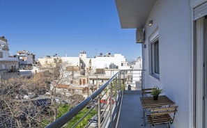 Uma varanda com vista para a paisagem urbana, uma mesa pequena com uma planta e um corrimão.