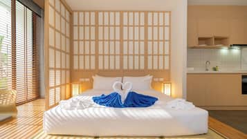 Quarto de hotel com uma cama grande, vista para o exterior e uma cozinha.