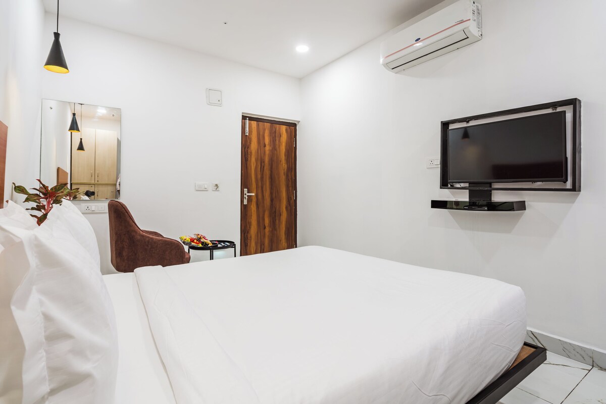 Quarto de hotel com cama, televisão na parede, guarda-roupa e espelho.
