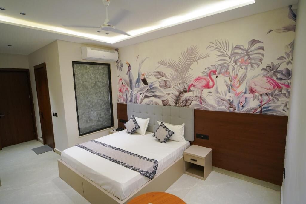 Quarto com cama, mesa de cabeceira e parede decorada com um mural floral.