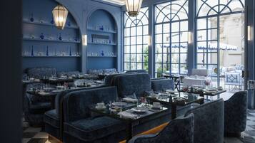 Restaurante com paredes azuis, janelas em arco e assentos estofados em azul.