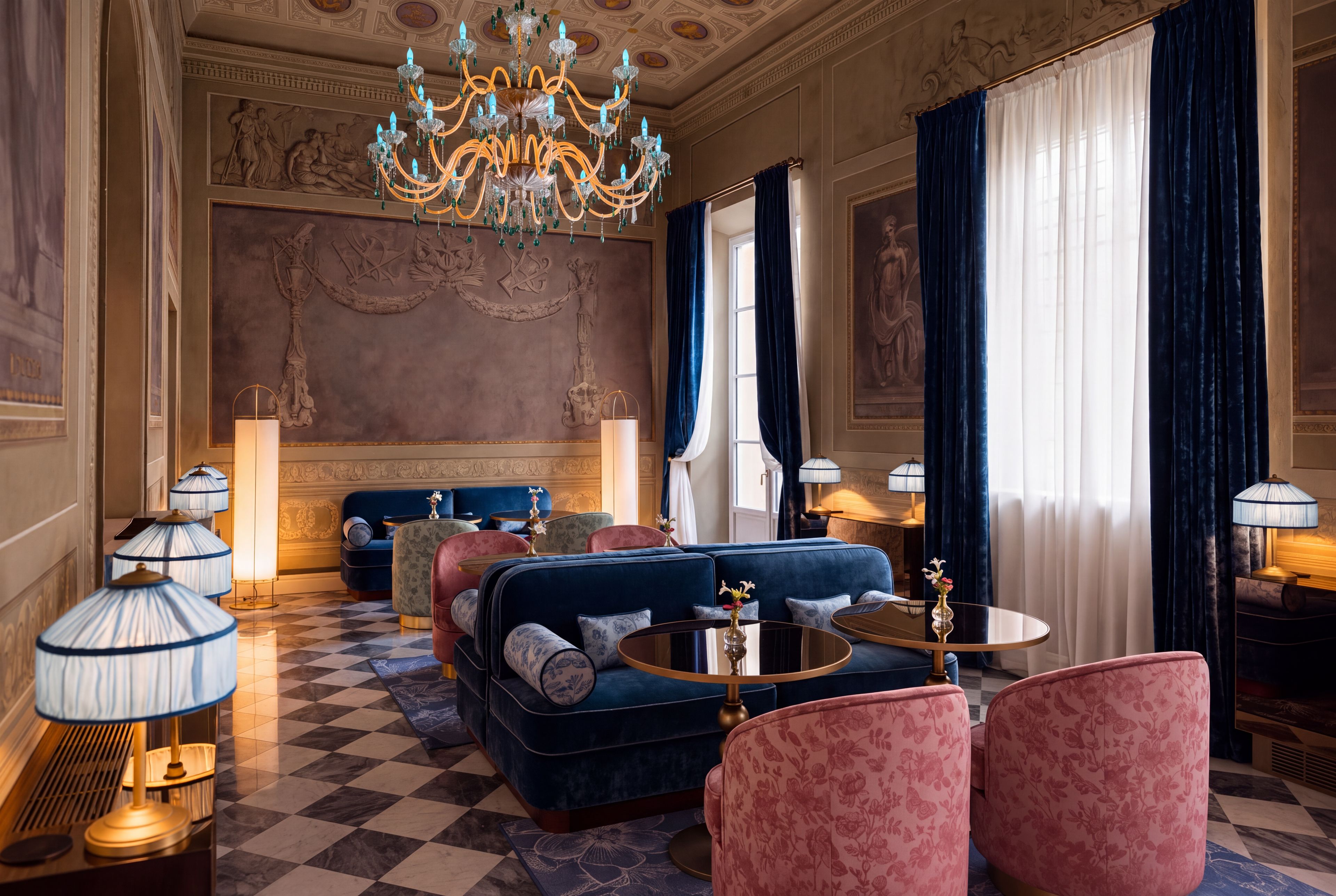 Quarto luxuoso com piso quadriculado, um lustre e um conjunto de sofás.