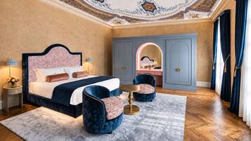 Quarto com cama, duas poltronas, escrivaninha e guarda-roupa.