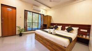 Quarto de hotel com uma cama grande, uma janela com cortinas, uma cabeceira de madeira e uma pequena mesa de cabeceira com uma planta.