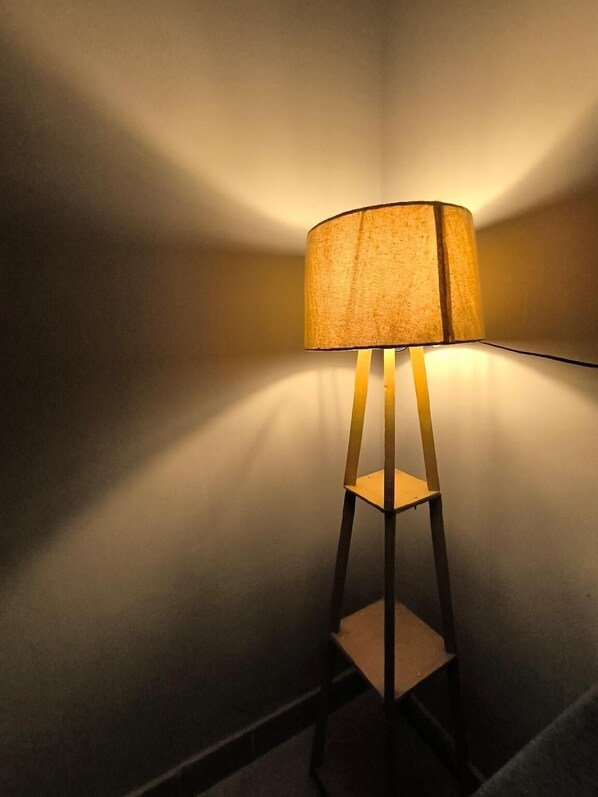 Luminária de chão com cúpula de tecido em um quarto com paredes lisas.