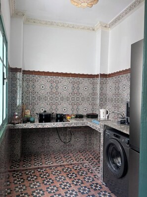 Cozinha compacta com azulejos estampados, máquina de lavar e pia.