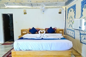 Quarto de hotel com cama, mesa de cabeceira, ar condicionado fixado na parede e decoração no teto.