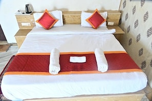 Quarto de hotel com cama, duas almofadas, mesa de cabeceira e parede com padrão.
