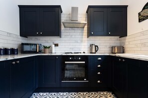 Cozinha moderna com armários escuros, micro-ondas, chaleira e forno embutido.