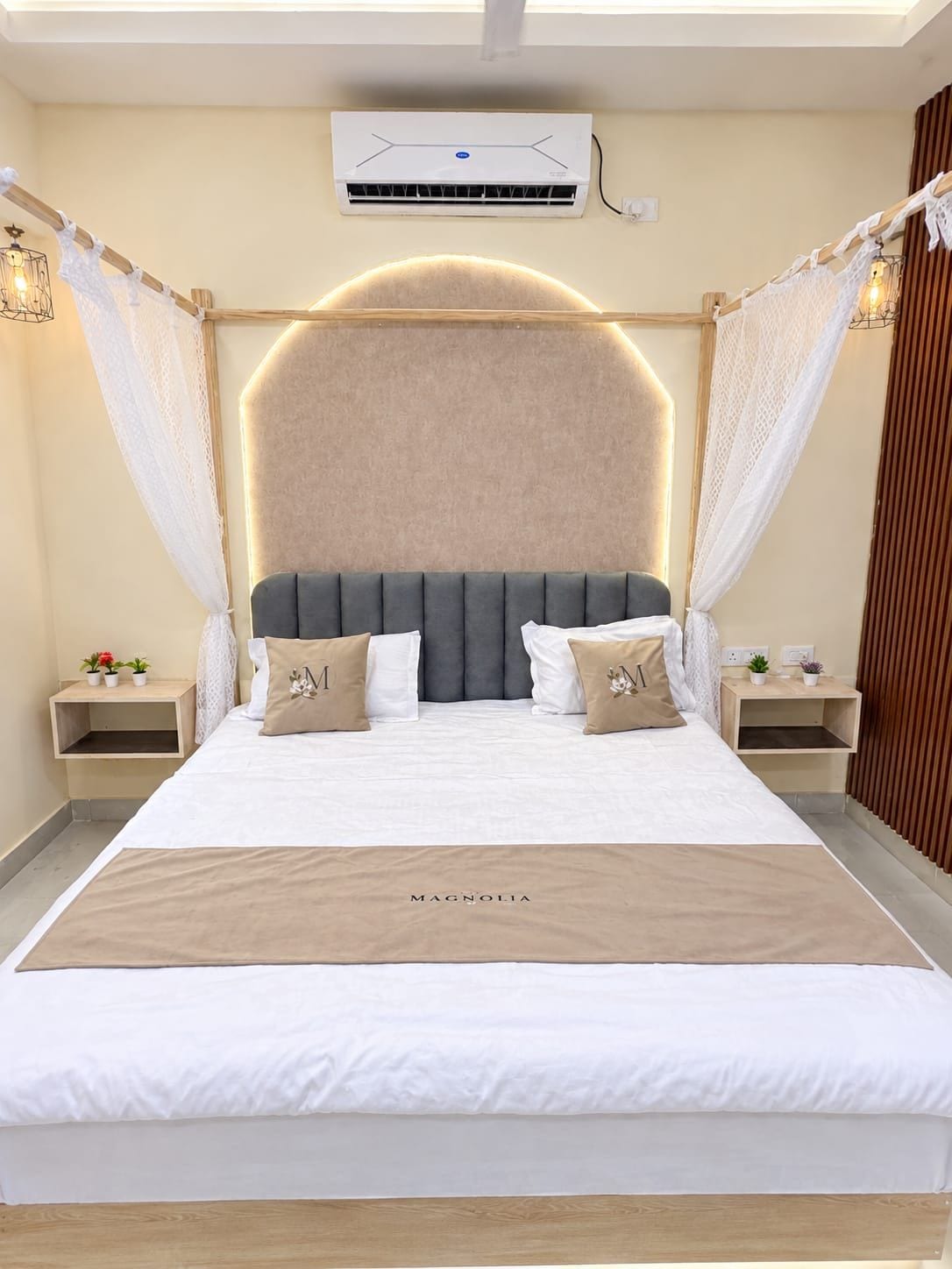 Quarto moderno com uma cama grande, cabeceira com iluminação integrada, mesas de cabeceira com abajures e ar condicionado na parede.
