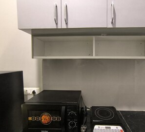 Cozinha com armários brancos, micro-ondas preto e fogão.