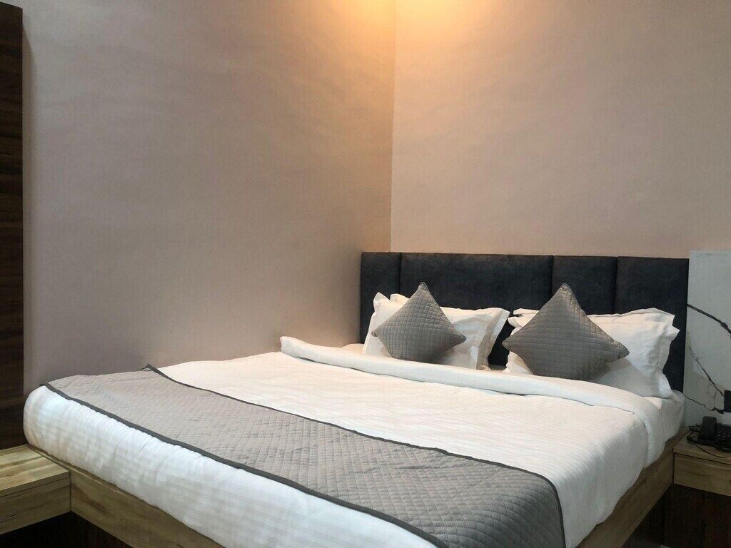 Cama bem arrumada com cabeceira, travesseiros e cobertor.