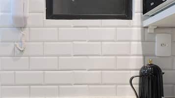 Uma cozinha com fogão a gás, cafeteira e micro-ondas.