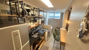 Cozinha compacta com forno embutido, pia e área de refeições com uma cadeira.
