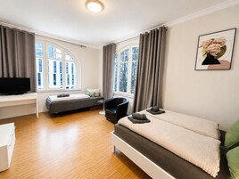 Quarto moderno com cama, escrivaninha, cadeira e televisão.
