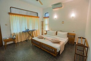 Quarto com cama, mesas de cabeceira, escrivaninha e cortinas.