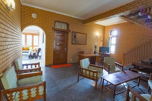 Quarto com paredes de tijolo, porta de madeira, televisão e disposição de assentos.
