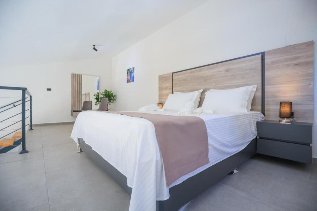 Quarto moderno com cama, mesas de cabeceira e criado-mudo.