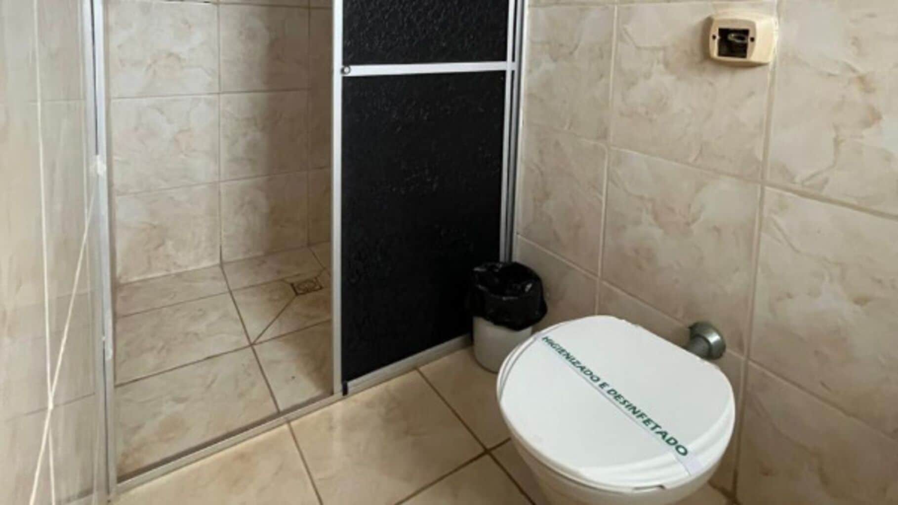 Casa de banho com sanita, um caixote de lixo preto e cabine de duche.