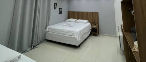Quarto com cama, mesa de cabeceira, guarda-roupa e ar condicionado na parede.