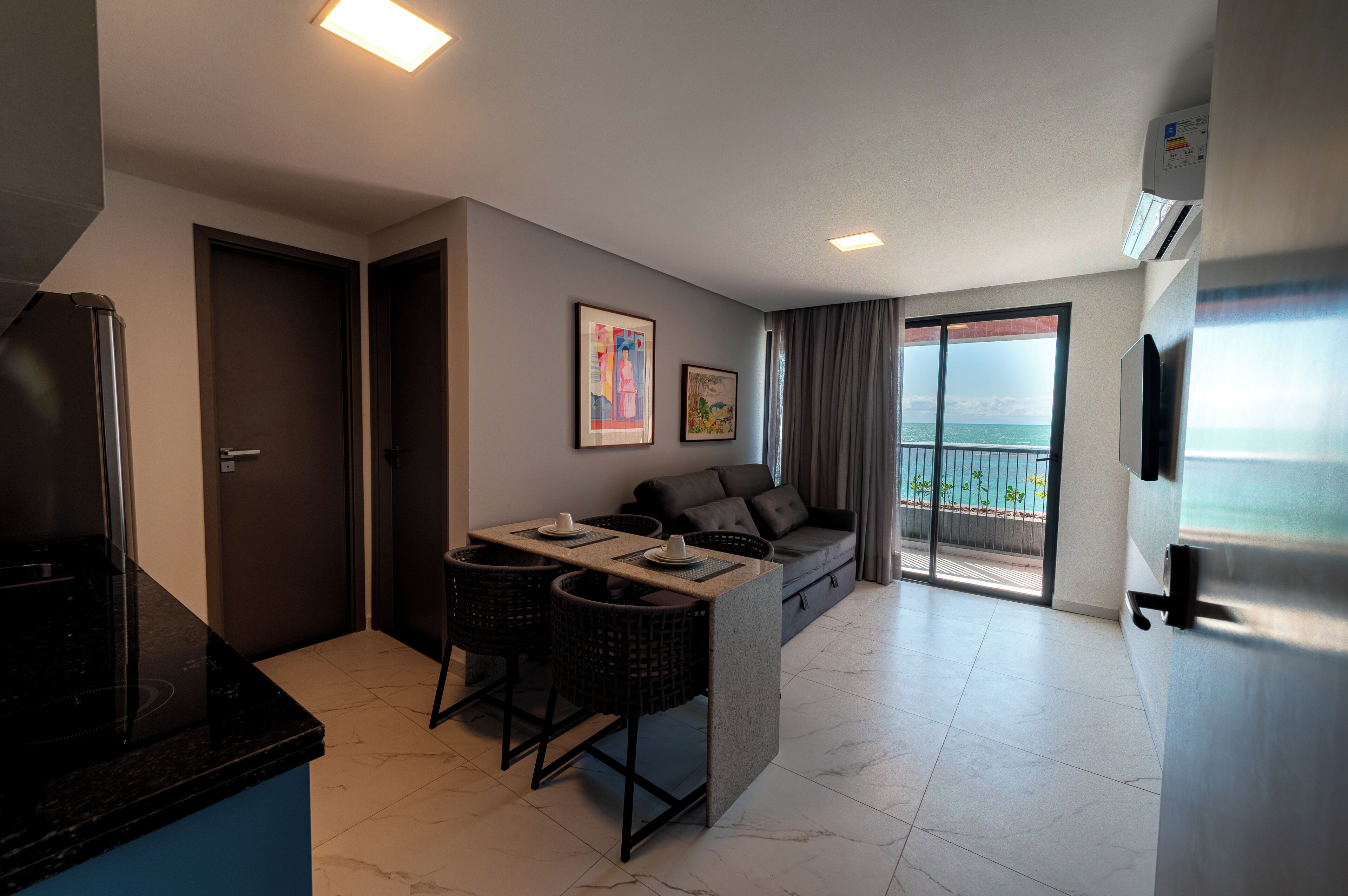 Espaço de estar moderno com cozinha, área de jantar e varanda com vista.