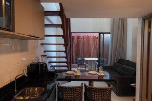 Uma cozinha moderna com área de refeições, uma escada e uma sala de estar com sofá.