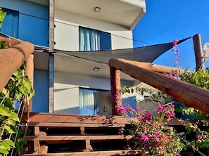 Um edifício moderno com varanda, guarda-corpos de madeira e vista para o céu.