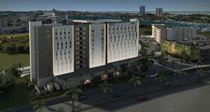 Um hotel moderno com um pátio central, rodeado por palmeiras e um porto de iates ao fundo.