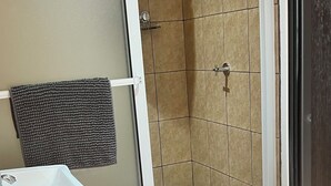 Casa de banho com chuveiro, sanita e lavatório.