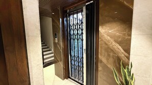 Um interior moderno com uma escada que leva a um andar superior, um portão de segurança e um vaso de plantas.
