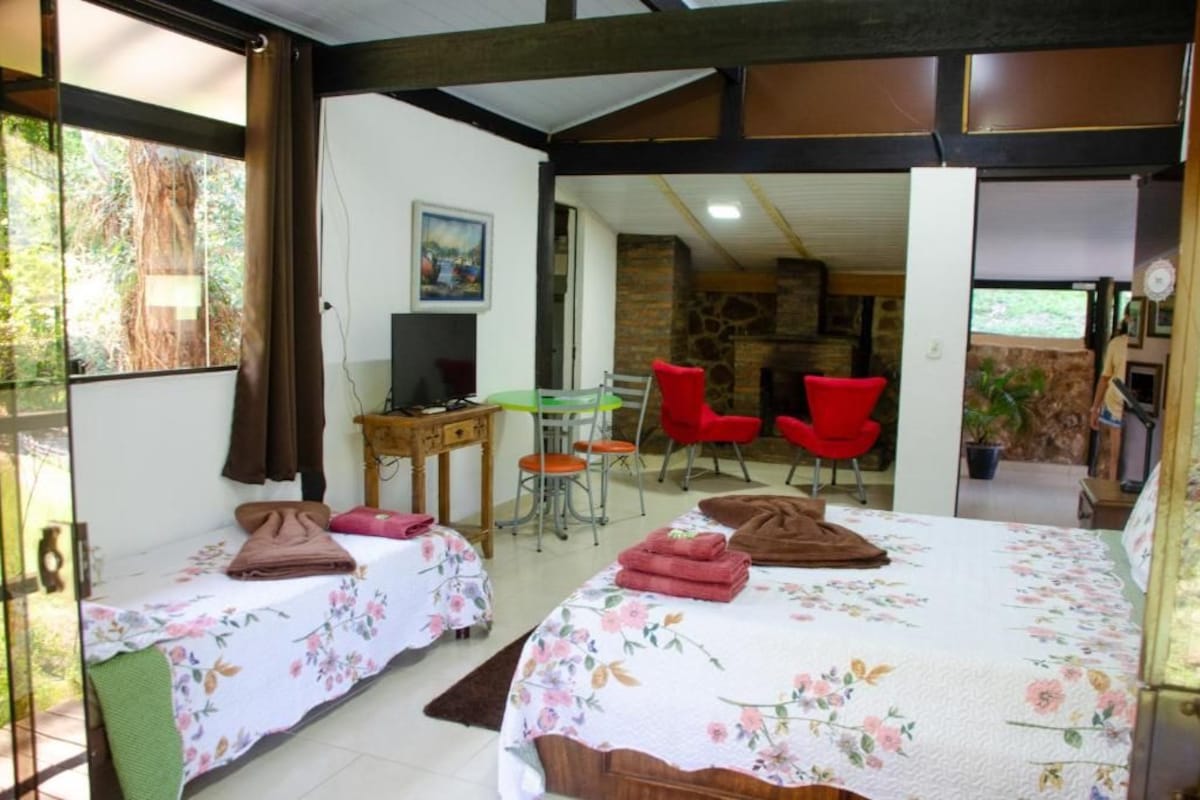 Quarto com duas camas, uma escrivaninha e uma lareira.